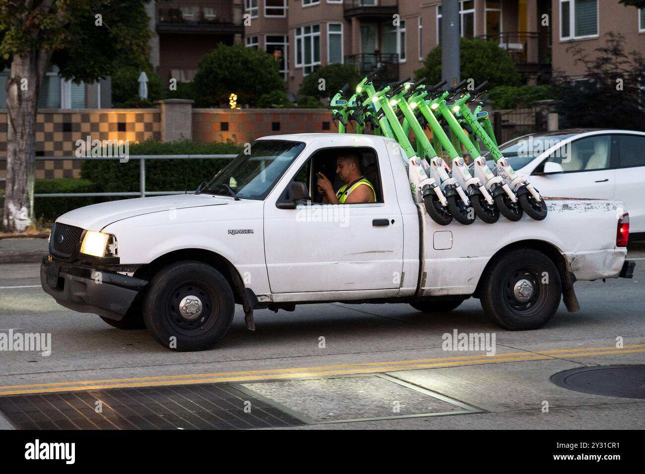 Seattle, USA. 8th Aug 2024. A gas powered vehicle picking up EV Lime ...