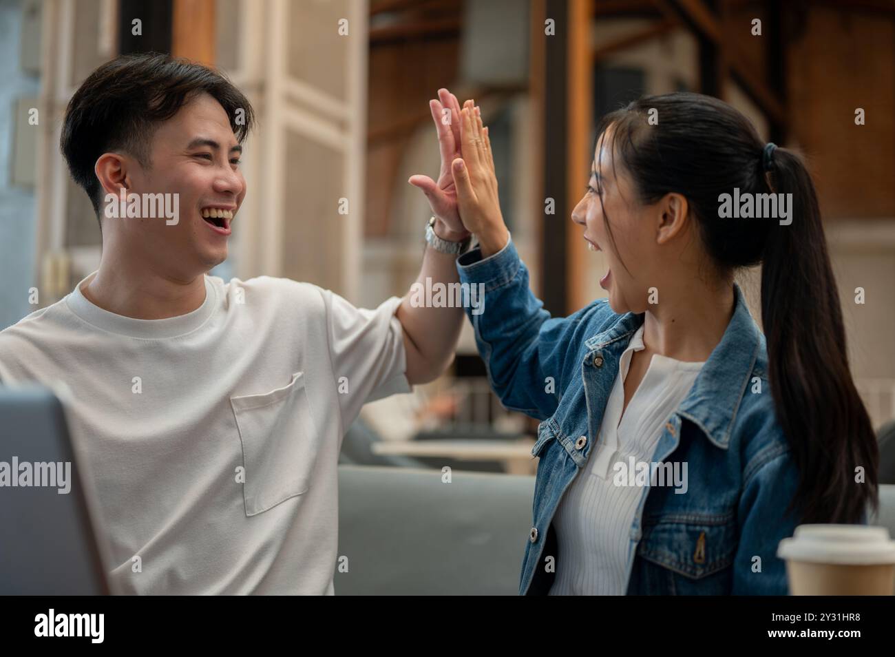 Two cheerful and excited young Asian friends are celebrating good news ...