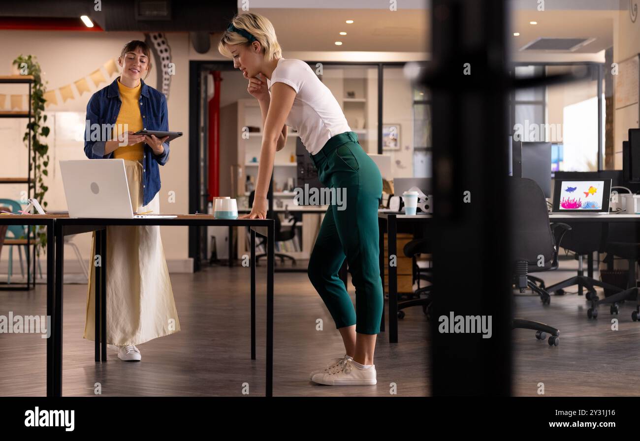 Collaborating in modern office, two multiracial women discussing ...