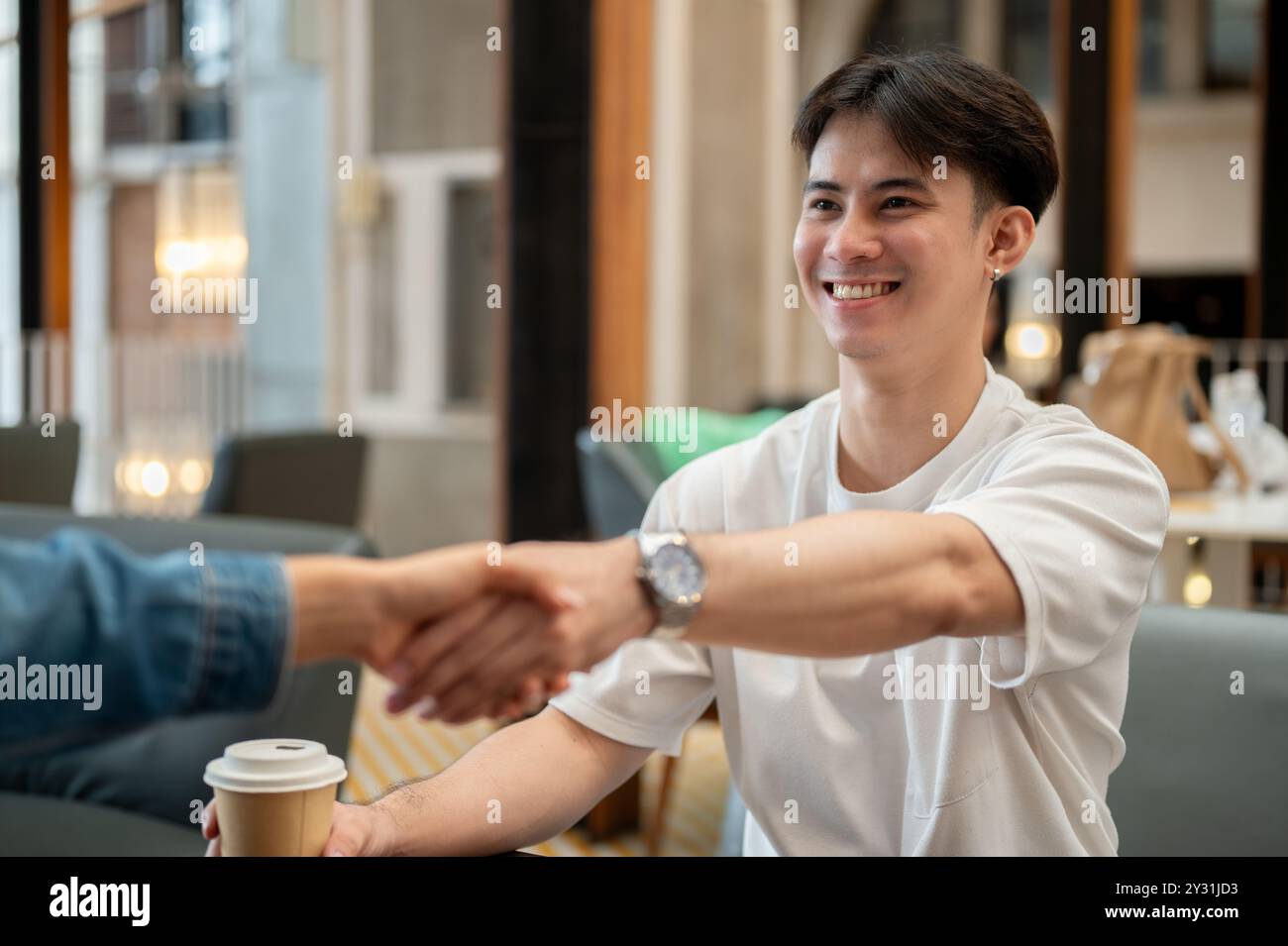 A happy, handsome young Asian man giving a handshake to his friend ...