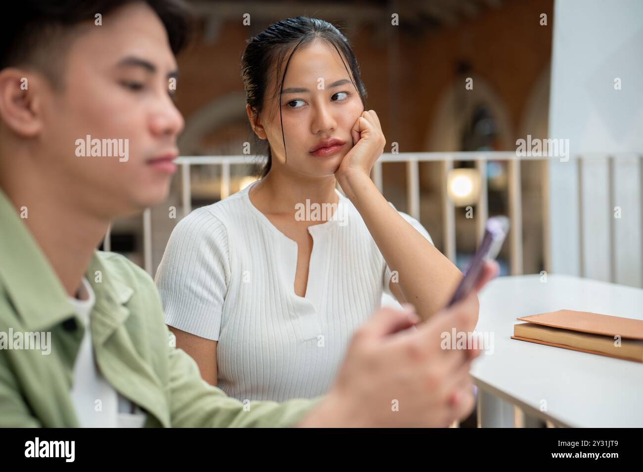 An unhappy, moody young Asian woman is feeling jealous, secretly ...