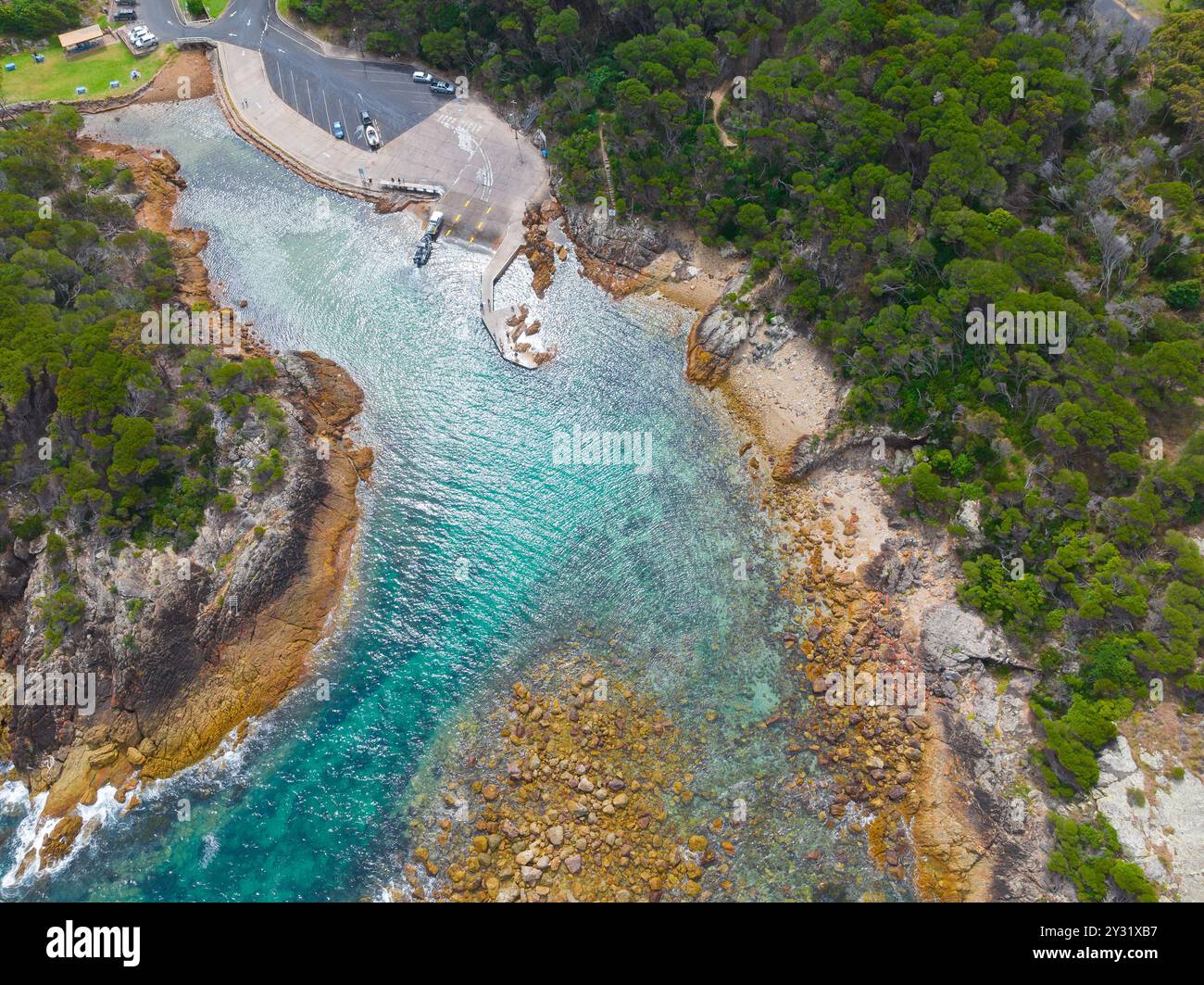 Aerial view of a coastal boat ramp and jetty in a calm coastal inlet at ...