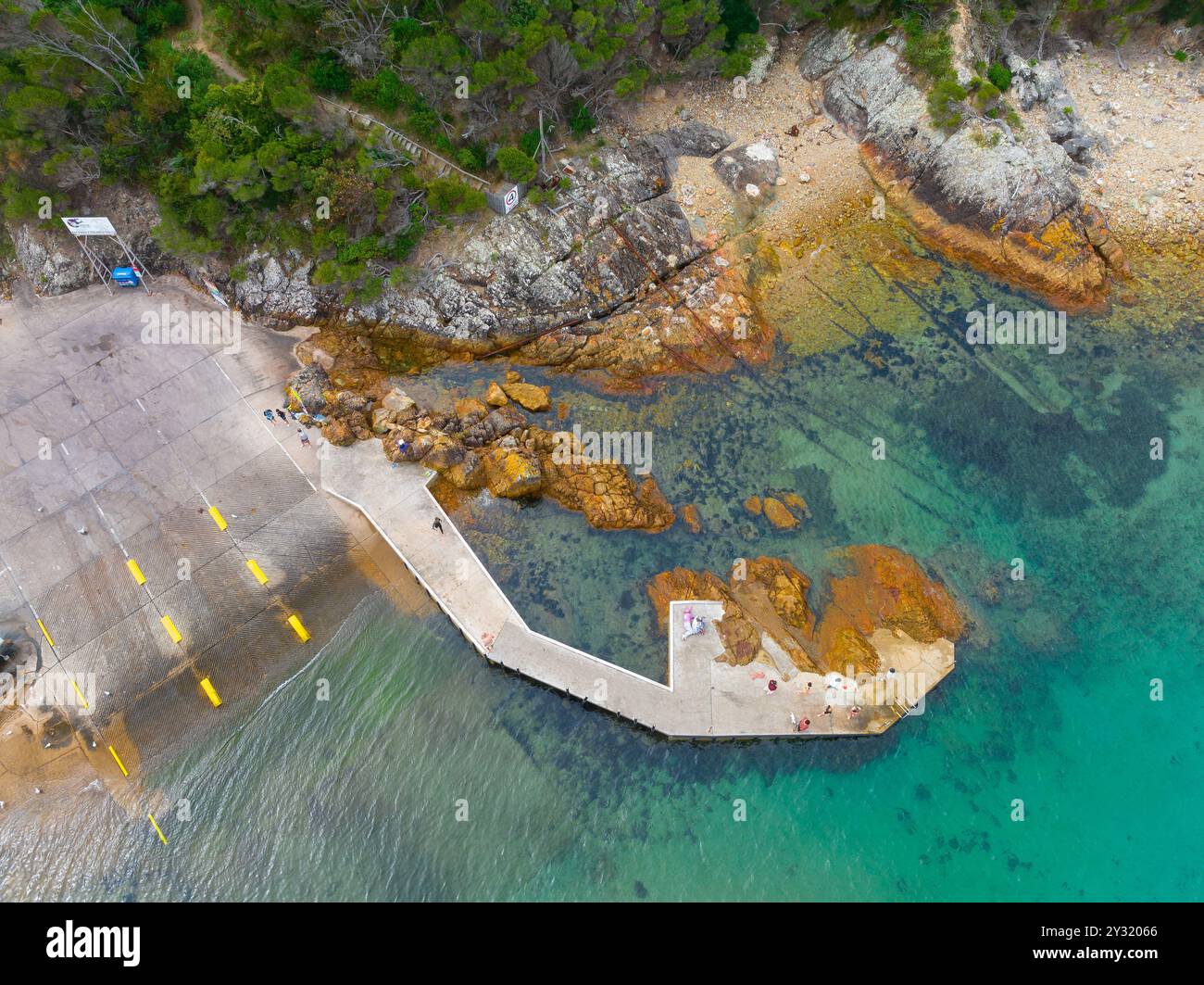 Aerial view of a coastal boat ramp and jetty in a calm coastal inlet at ...