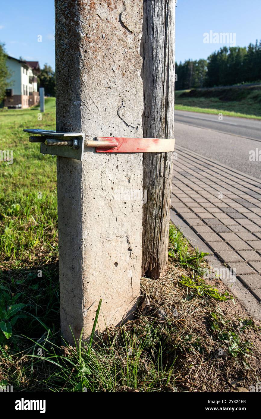 A wooden log attached to a concrete post with a turnbuckle. Fixing the ...