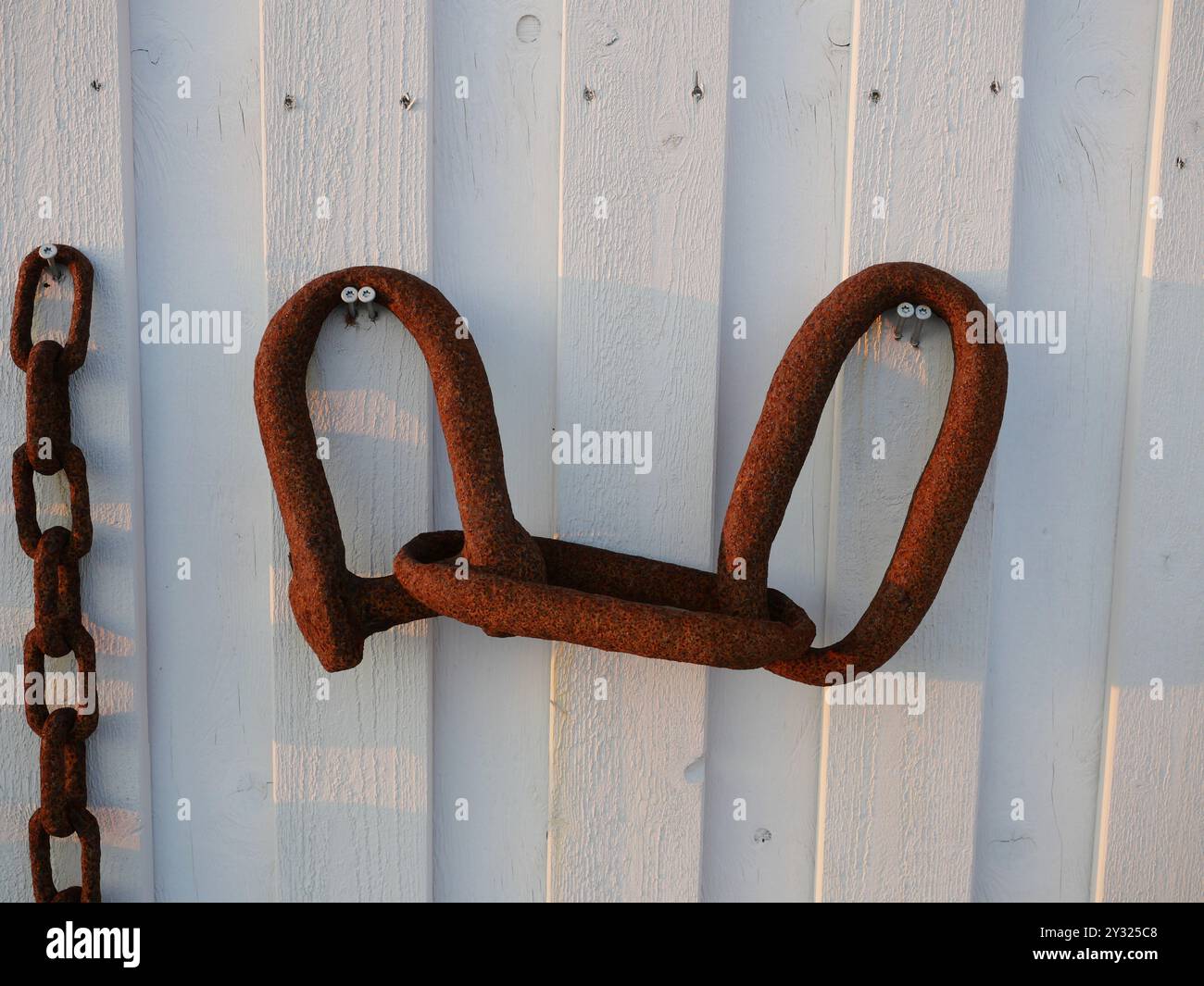 a white wooden wall in the harbor with various iron chains hanging on ...