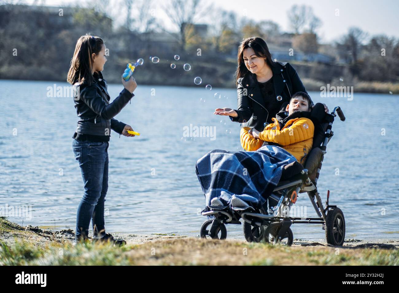 Mother and children enjoying outdoor time by the lake, inclusive family ...