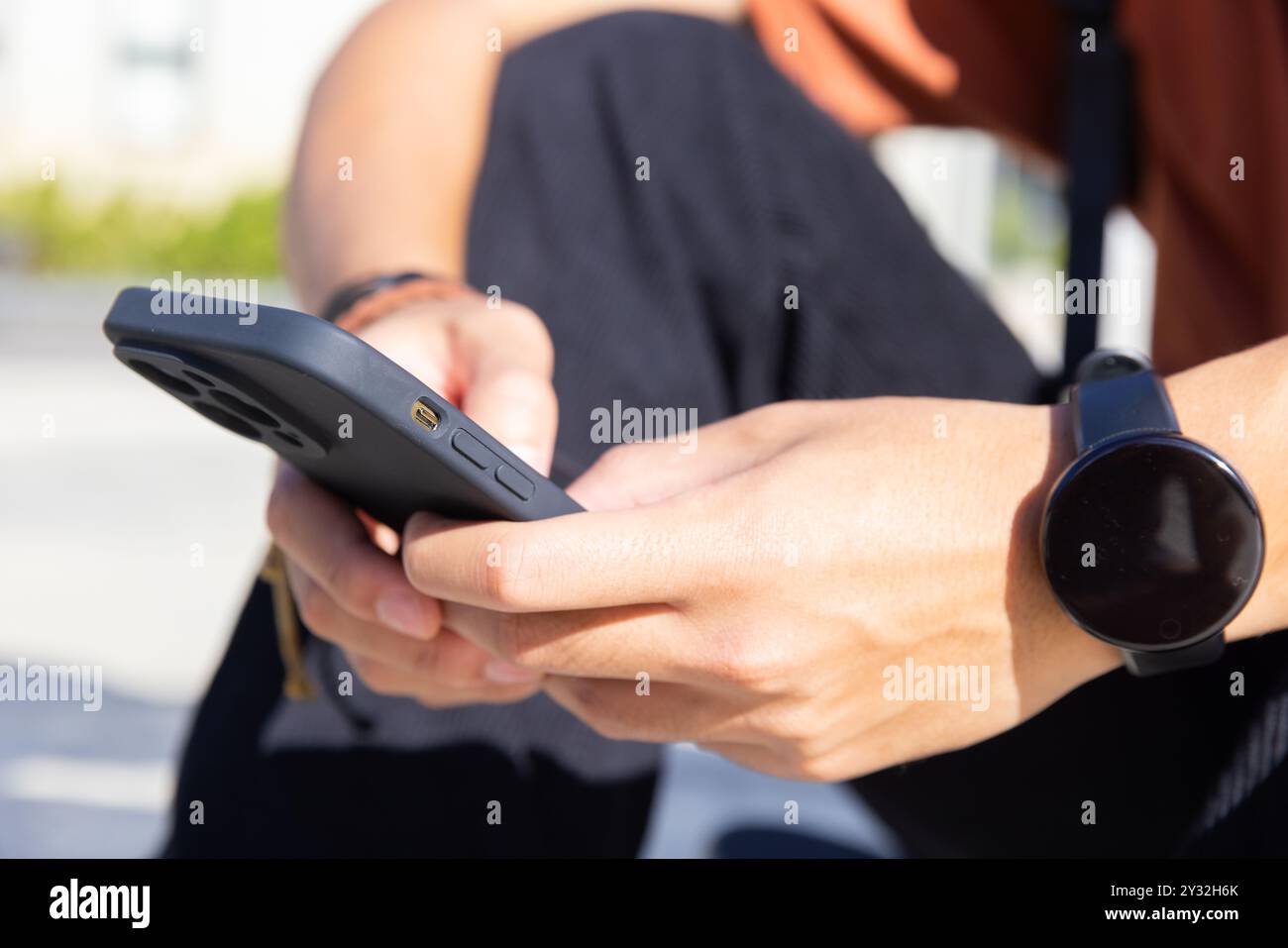 Texting on smartphone, asian teenage boy sitting outdoors during ...