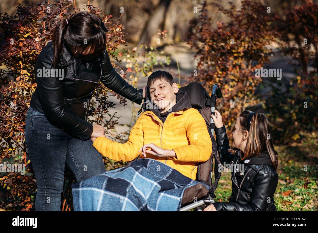 Mother and sibling bonding with child in wheelchair during outdoor time ...