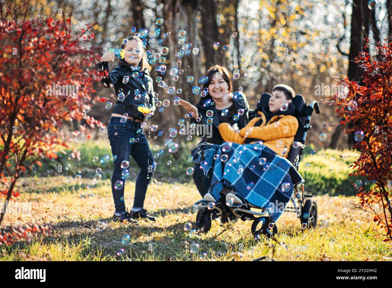 Mother and sibling spending quality time with child in wheelchair ...