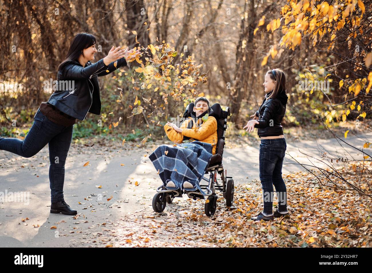 Mother and children enjoying autumn leaves, special needs bonding ...