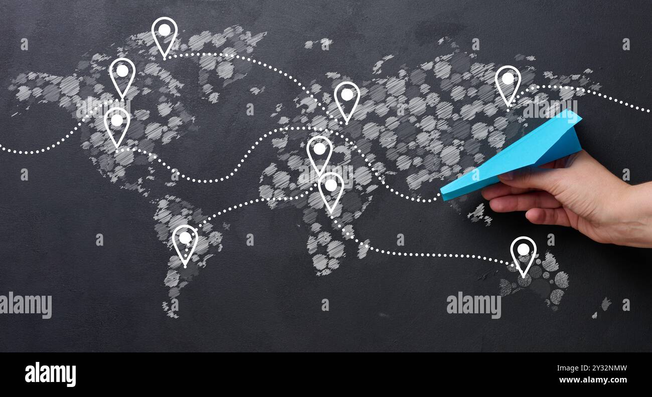 Hand holding blue paper airplane against world map background with ...