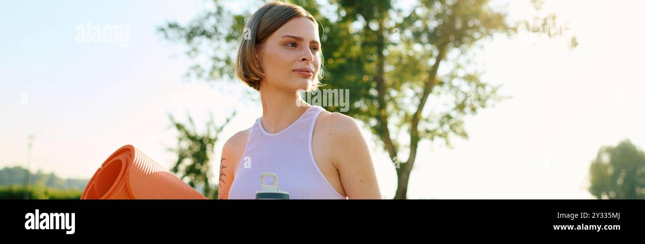 A beautiful woman strolls through a park, holding workout equipment ...