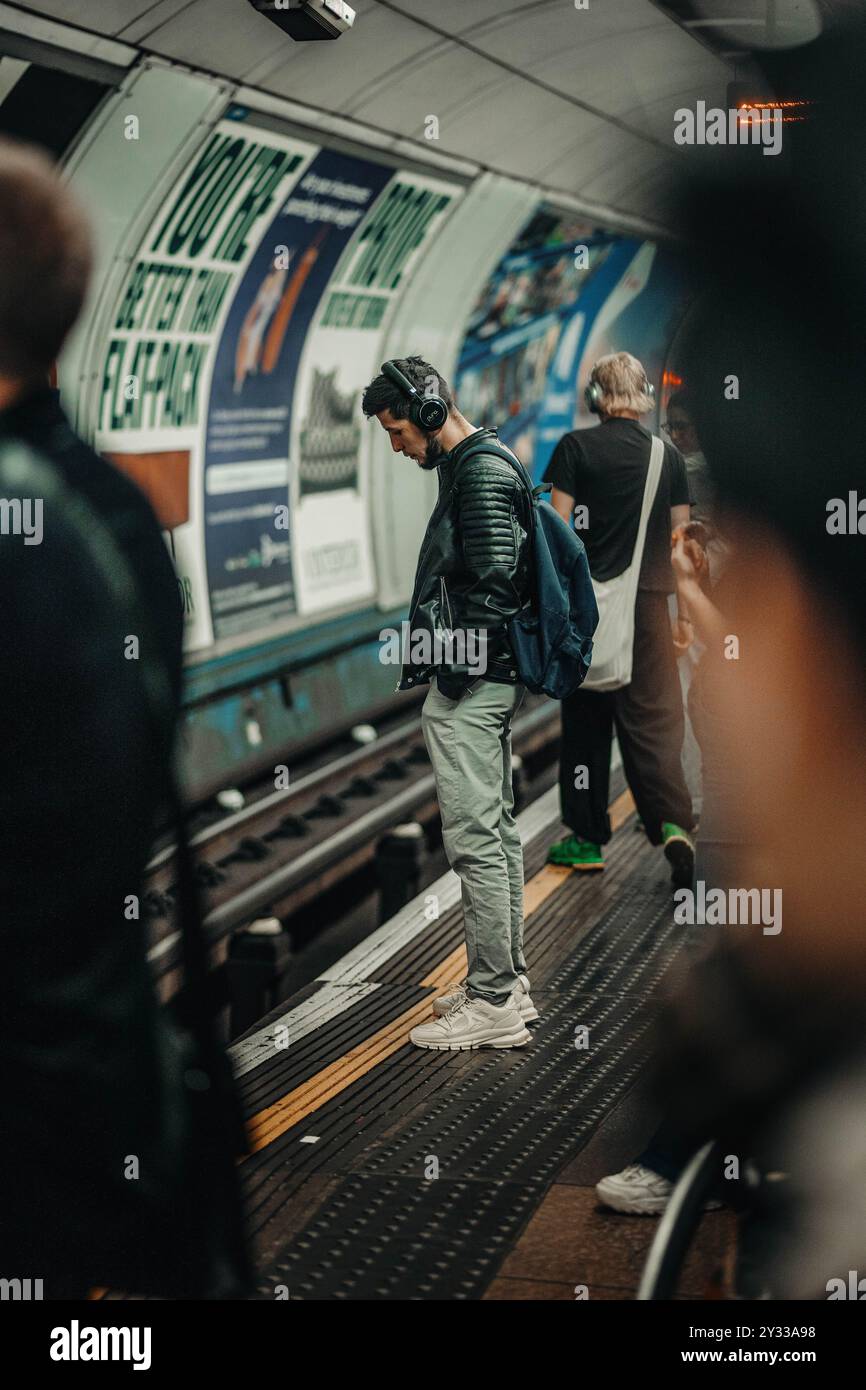 Man waiting for London Underground with headphones on Stock Photo - Alamy