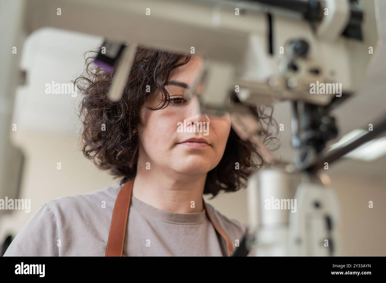 A woman tanner sews a leather belt on a sewing machine Stock Photo - Alamy