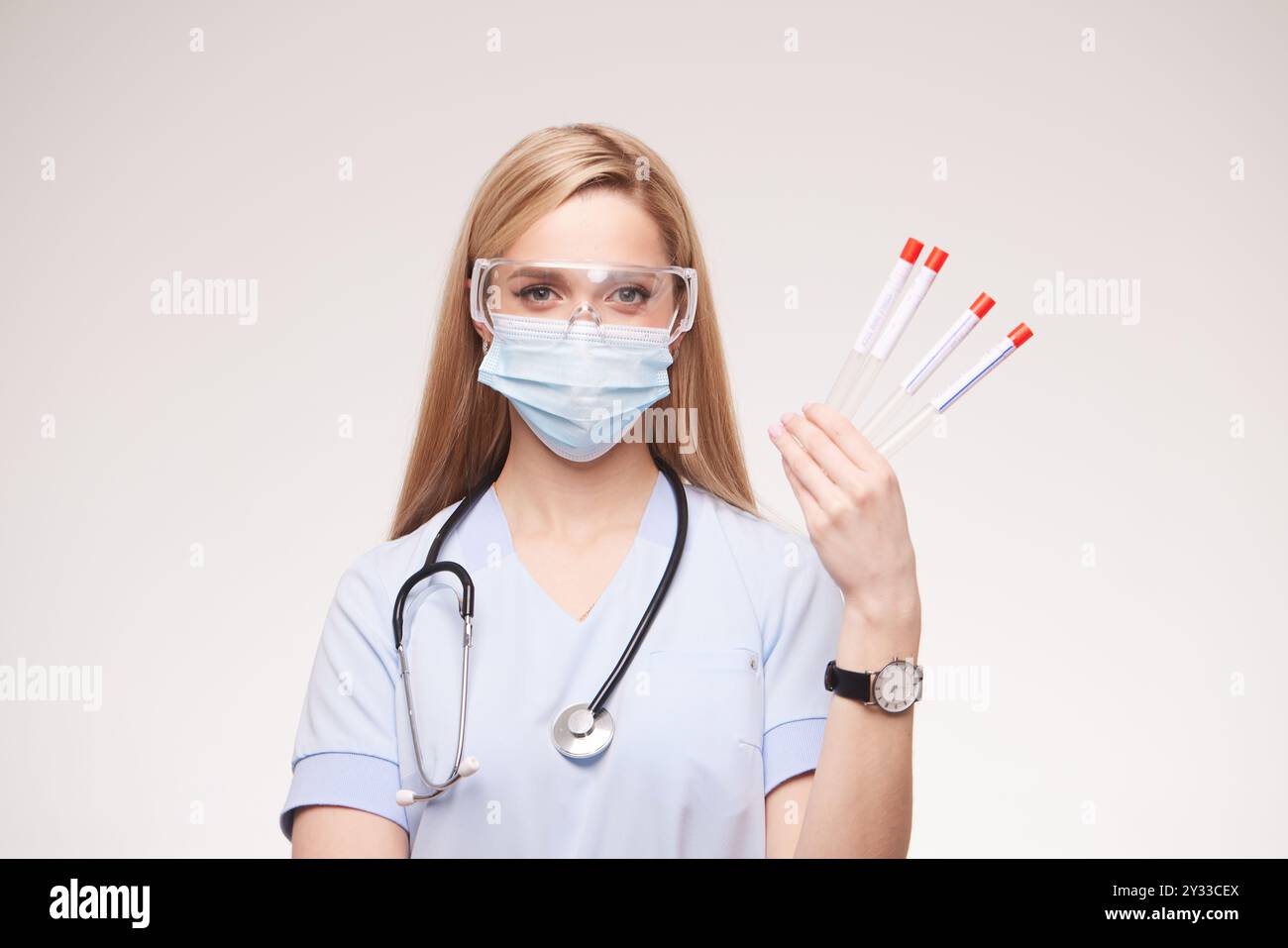 A female healthcare professional wearing a mask and protective goggles ...