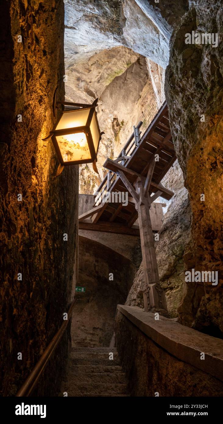 A medieval stone stairway with a wooden bridge and lantern in a cave ...