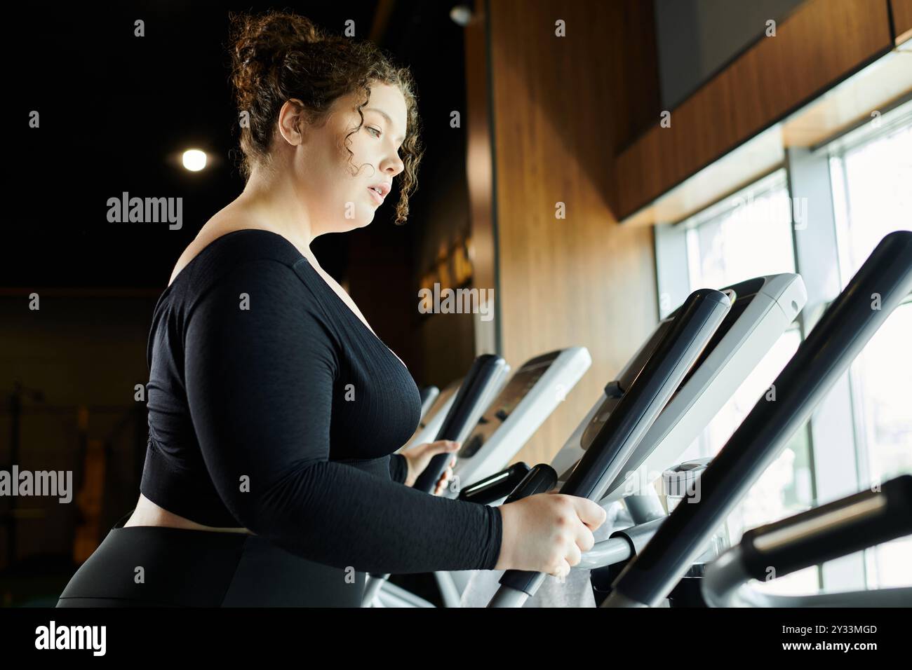 A confident young woman engages in a workout routine at the gym, embracing her body and fitness ...