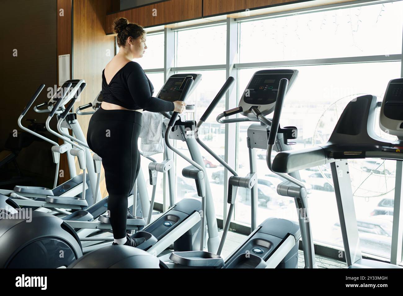A plus-size woman confidently exercises on an elliptical, celebrating ...