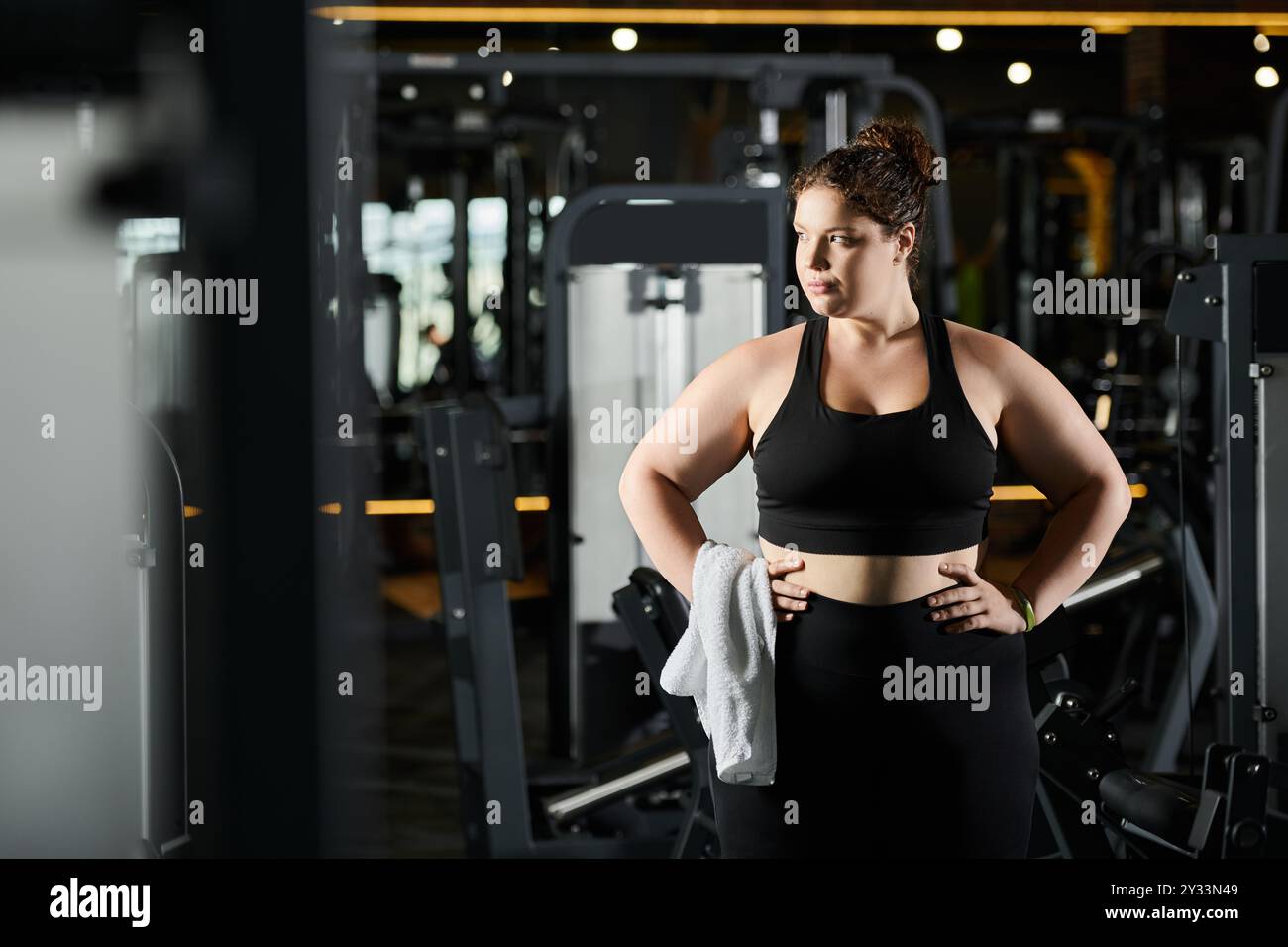 A confident young woman in active wear exercises in a gym, celebrating ...