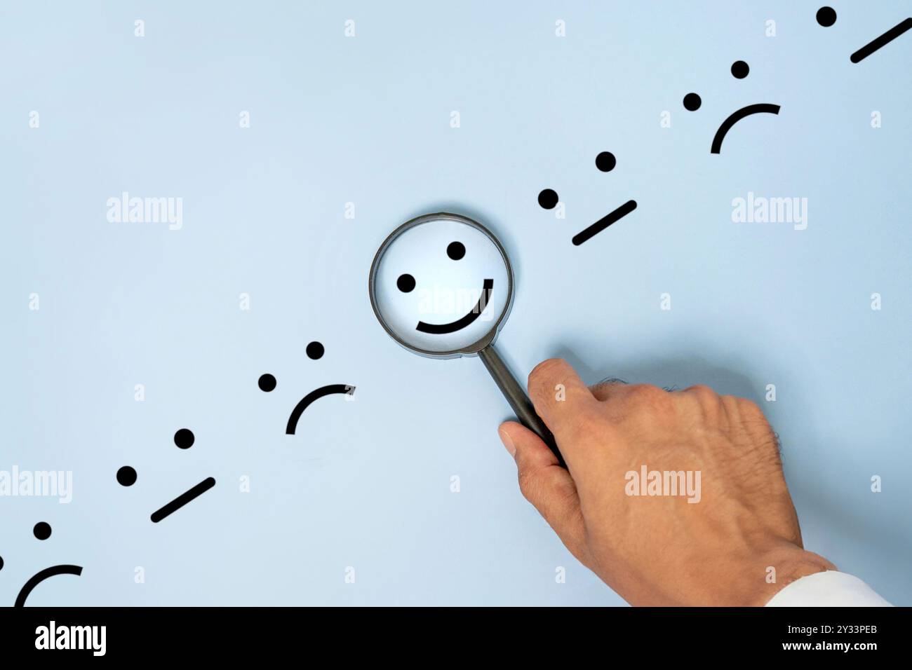 A hand holding a magnifying glass over a blue background with drawings ...