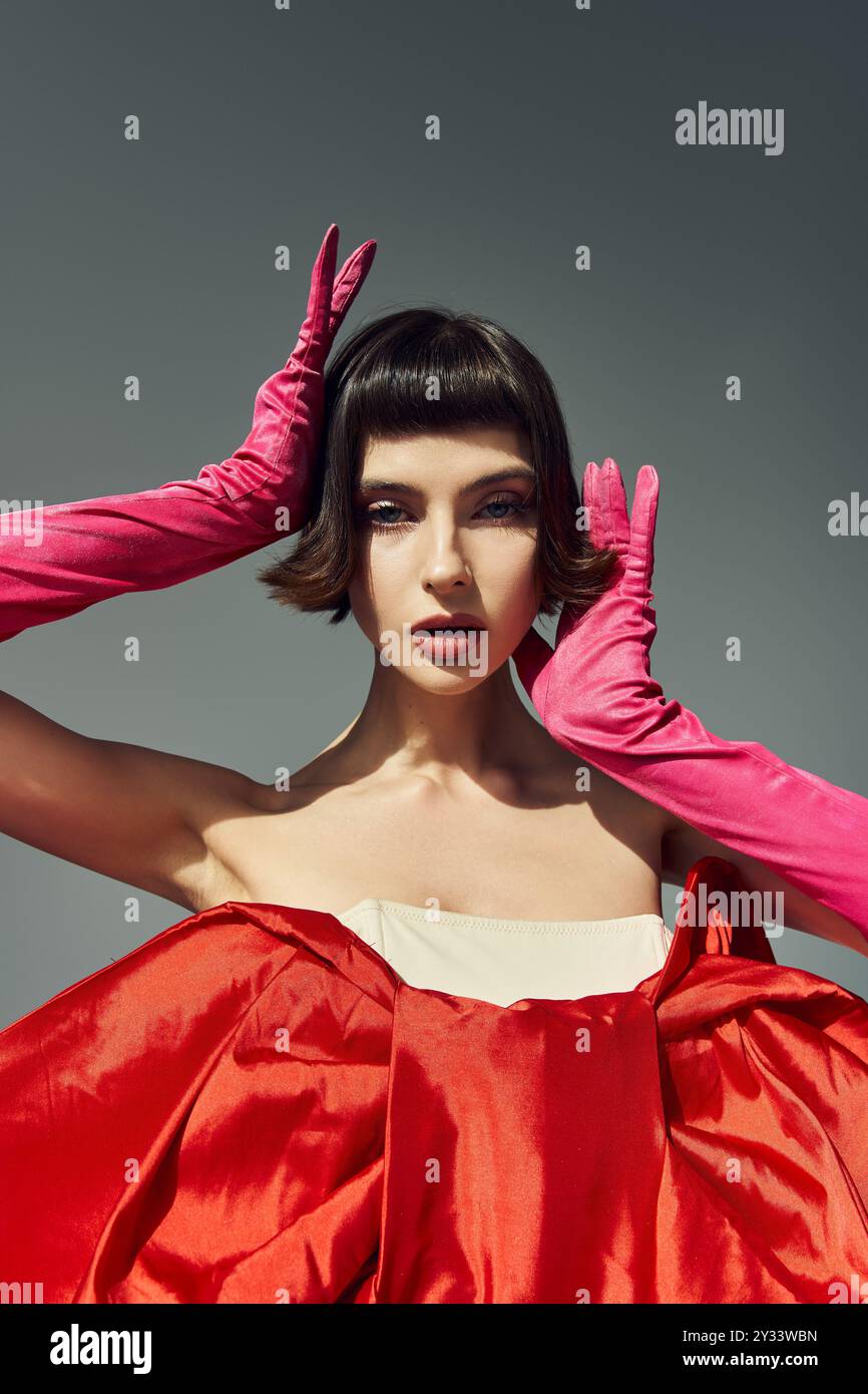 A stylish young woman poses gracefully in a striking red dress with a ...
