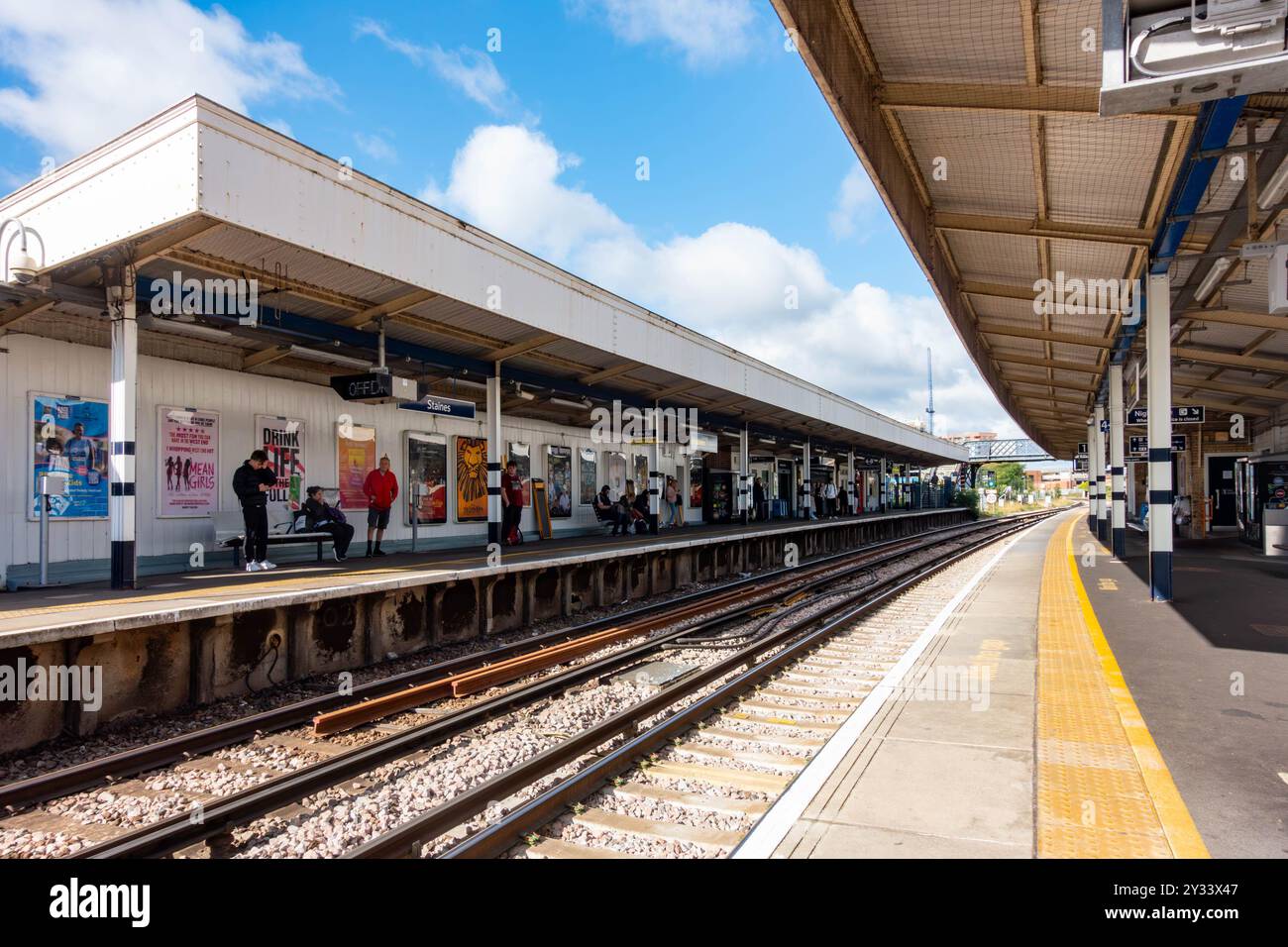A view along the platform at Staines railway station with passengers ...