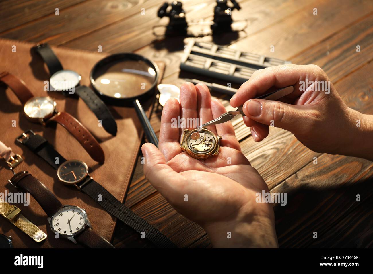 Man fixing mechanism of vintage wrist watch at wooden table, closeup ...