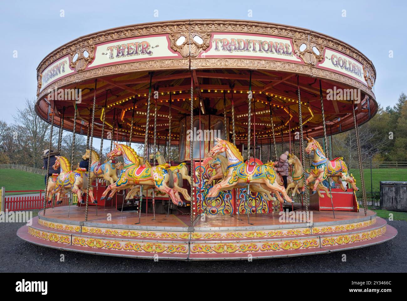 A carousel fairground ride with a young child and a couple of adults ...