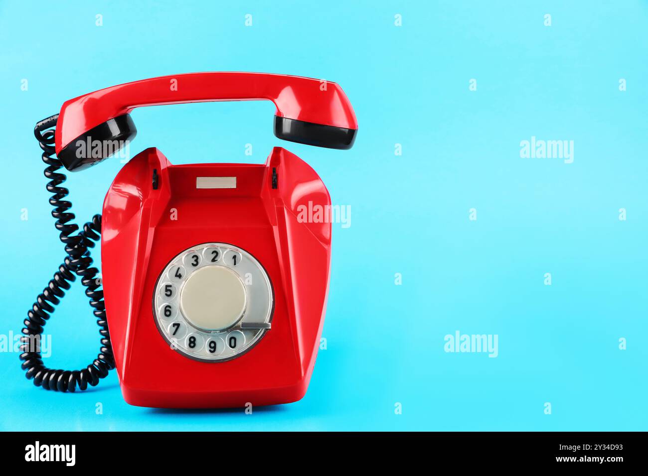 Red telephone with handset on light blue background, space for text ...