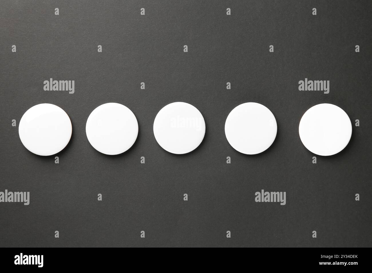Blank white button badges on black background, top view. Mockup for ...