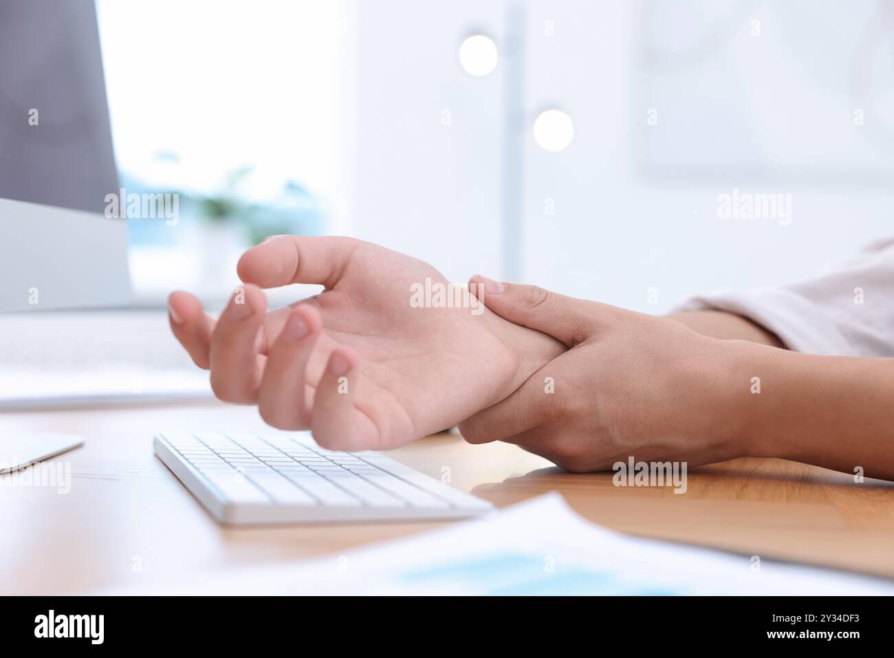 Man suffering from pain in wrist while working on computer at table ...
