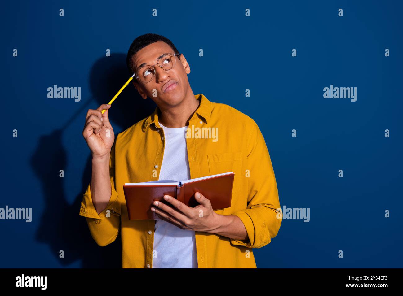 Photo of young intelligent student man in yellow shirt hold his ...