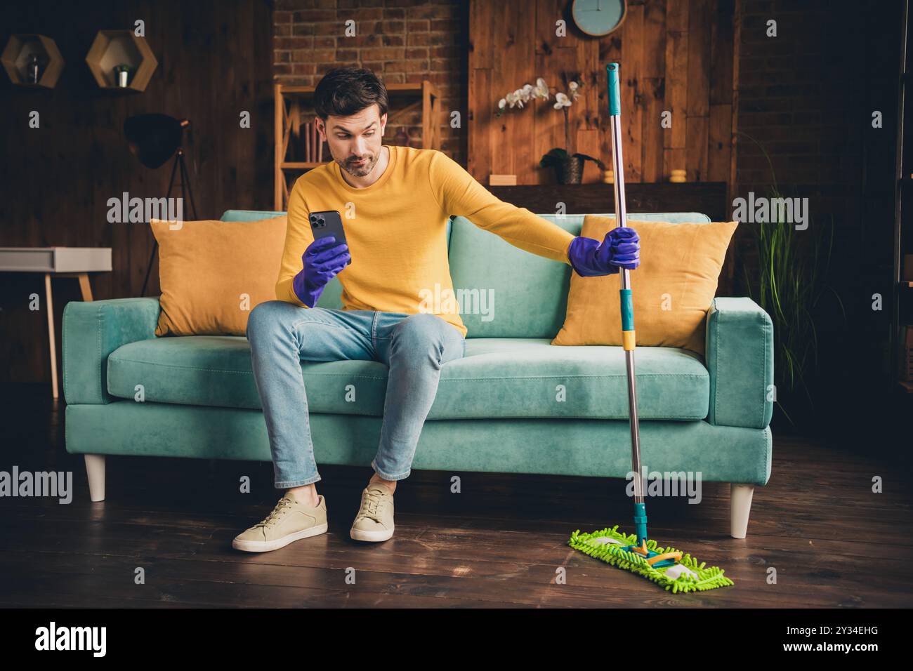 Full body photo of nice young man lying sofa mopping floor cleaning ...