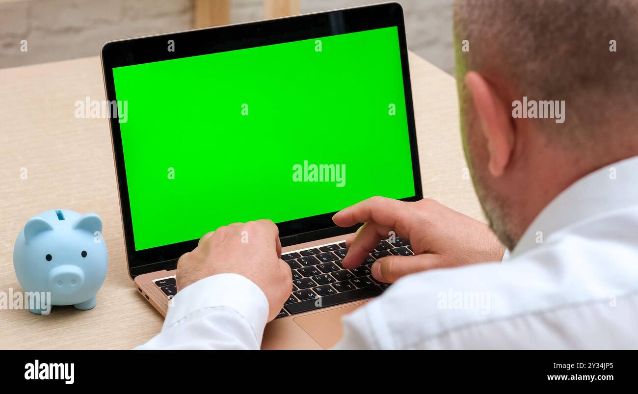 Man using green screen blank laptop next to piggy bank. Online banking ...