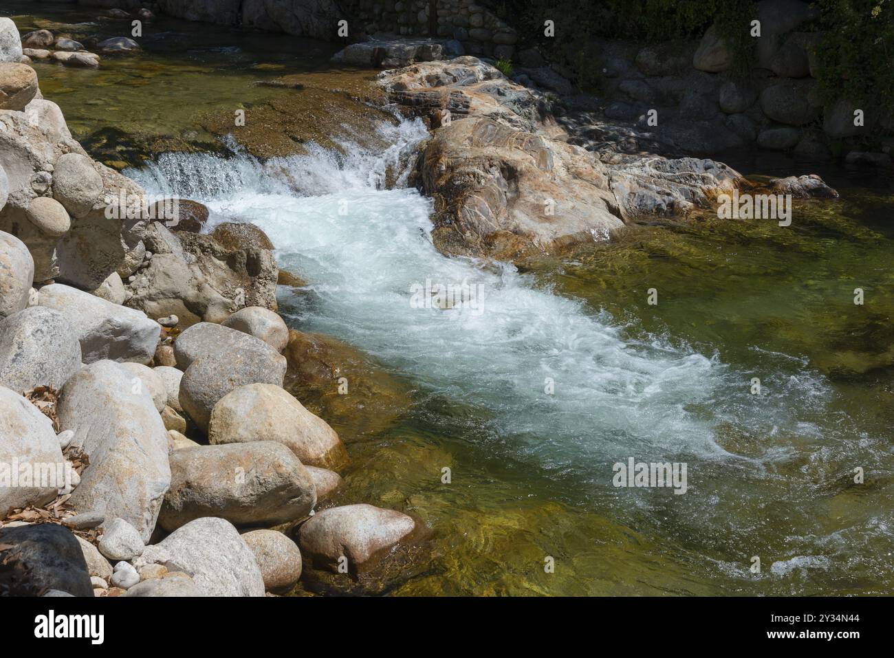 Clear water flows over rocks in a small, natural river, Piscina natural ...
