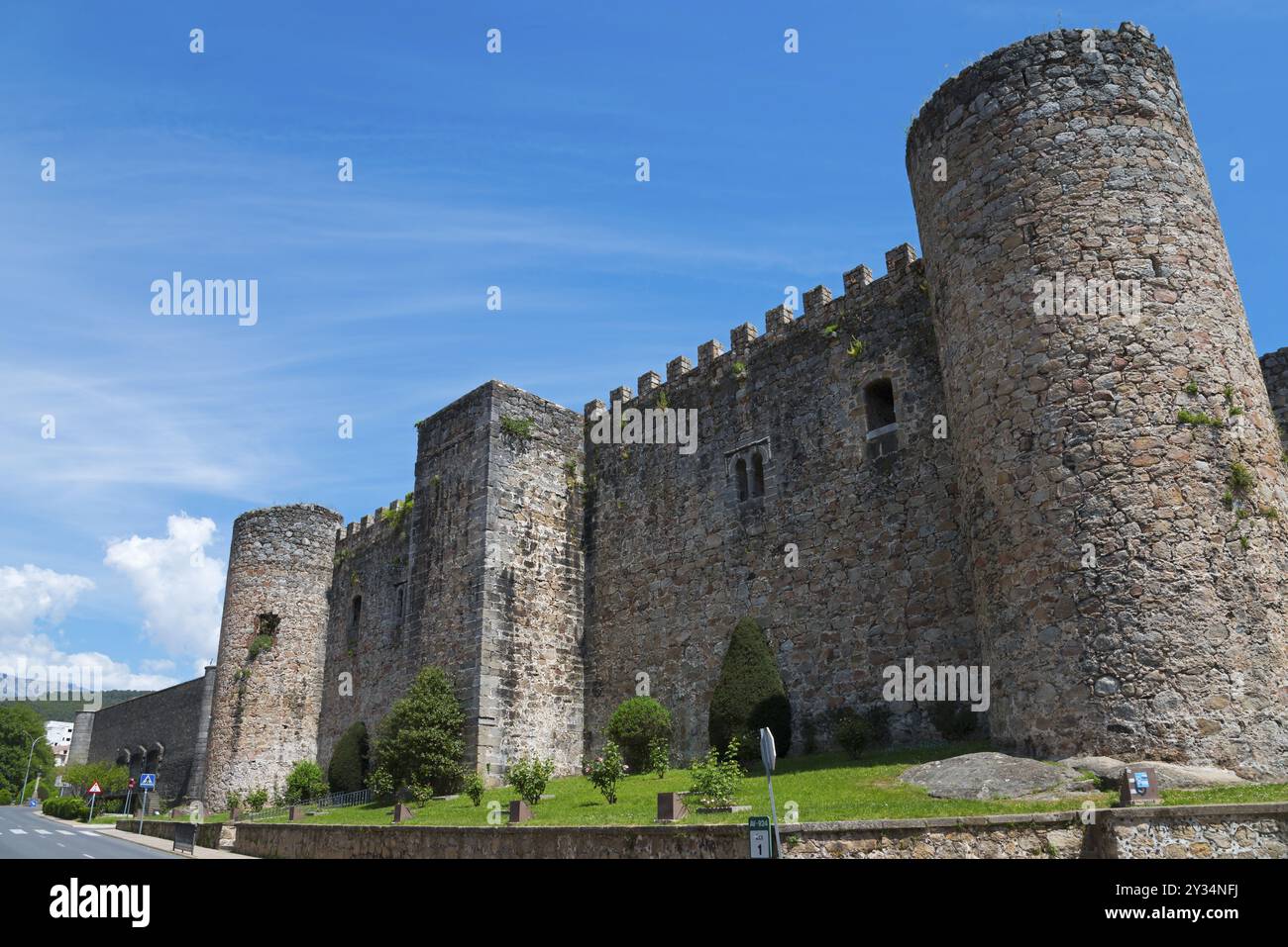 Massive medieval castle wall with stone towers under a clear blue sky ...