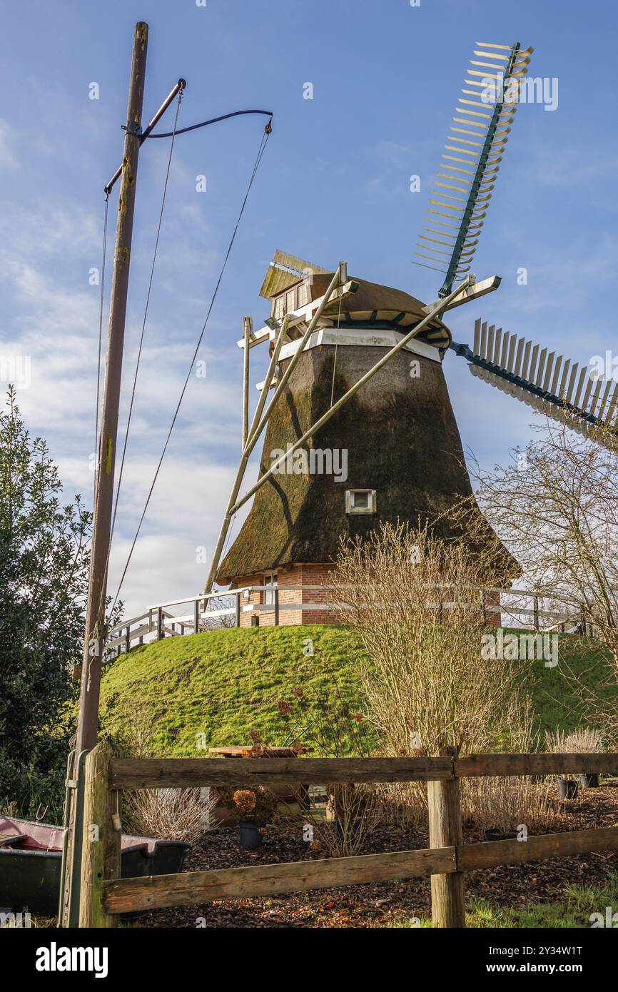 Windmill with thatched roof and wooden mast in the foreground ...