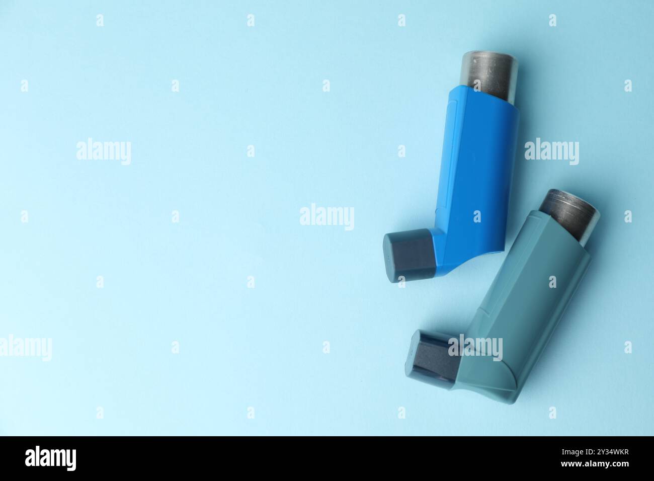 Asthma inhalers on light blue background, top view. Space for text ...