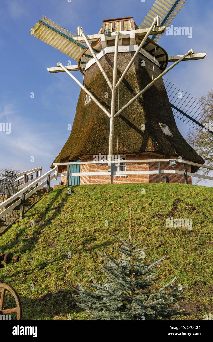A wide view of a windmill on a grassy hill under a bright blue sky ...