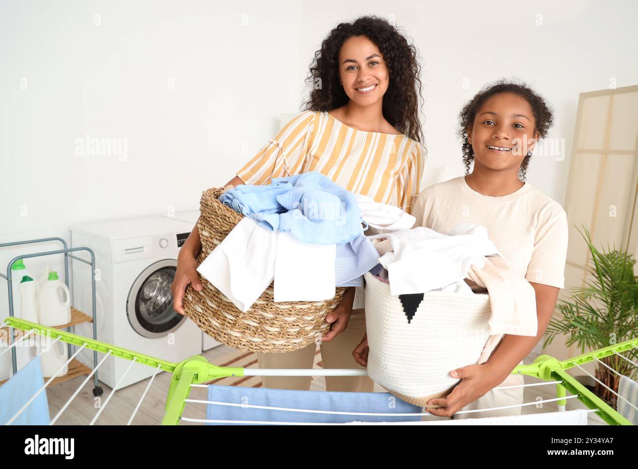 African-American woman and her daughter with laundry at home Stock ...