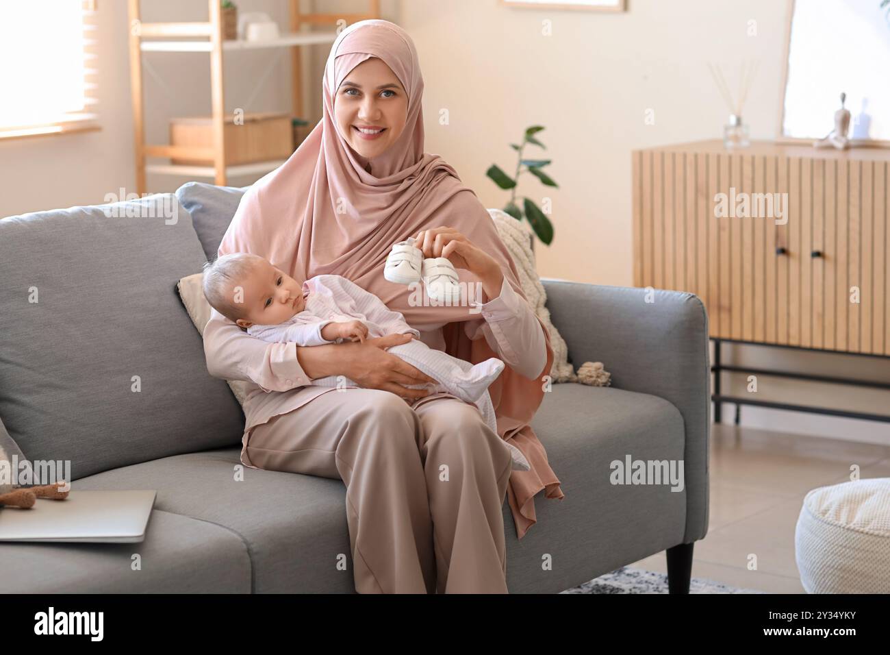 Happy Muslim mother in hijab with cute little baby and boots sitting on ...