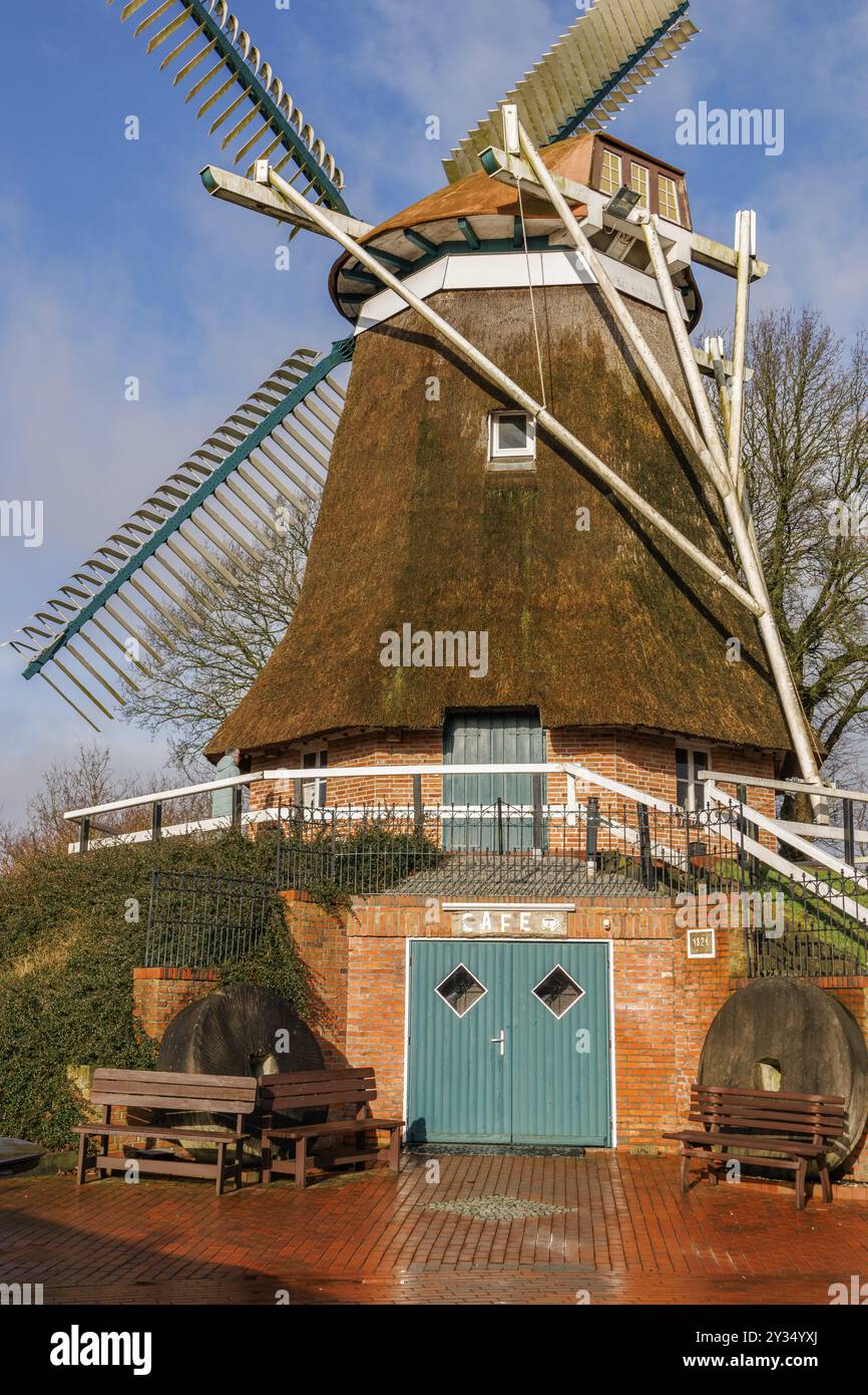 Windmill with wooden doors, thatched roof and benches, in front of a ...