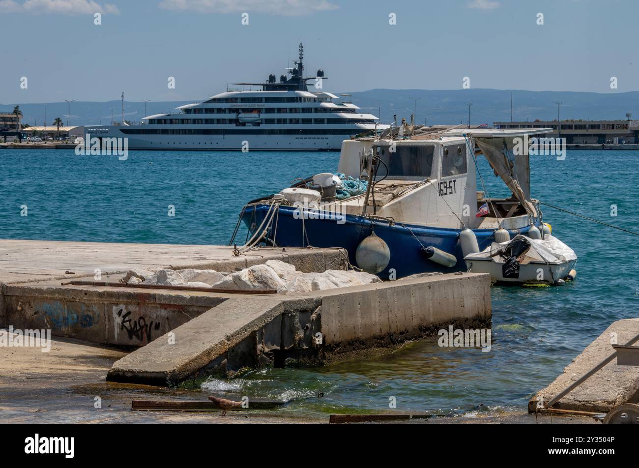 old fishing boat in front of luxury superyacht in the harbour in split ...