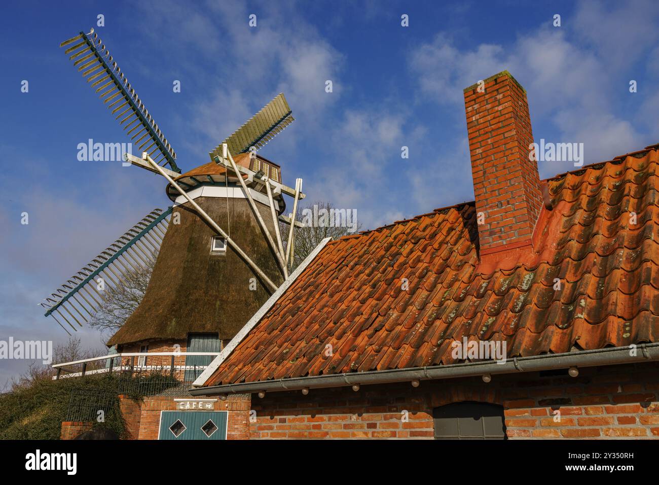 Windmill and brick building with roof tiles and chimney in front of a ...