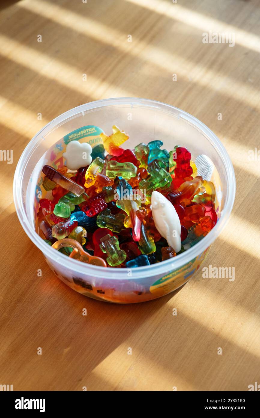 Variety of colored jelly gummy candy in plastic round container. Set on ...