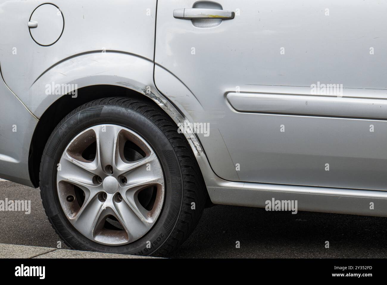 Dented and scratched car wheel arch bodywork. Generic car, front view ...