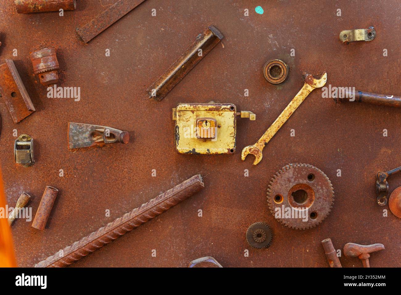 A collection of rusty metal components is resting on a rusty surface ...