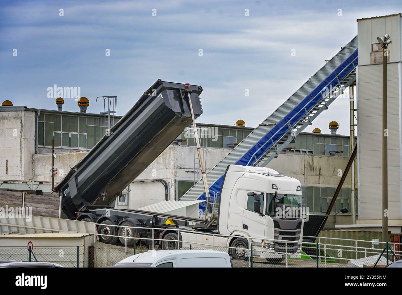 Modern white truck dumping sand beside the conveyor belt in the ...