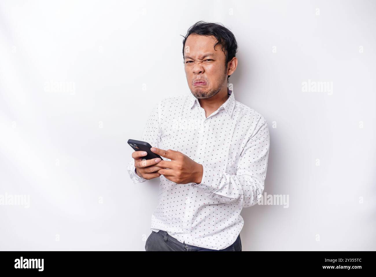An angry young Asian man looks disgruntled wearing a white shirt ...