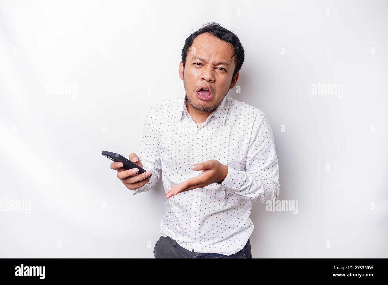 An angry young Asian man looks disgruntled wearing a white shirt ...